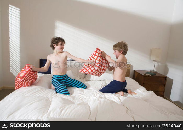 Bare Chested Brothers Rough Housing And Pillow Fighting On Bed In