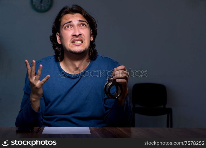 The young convict man sitting in dark room. Young convict man sitting ...